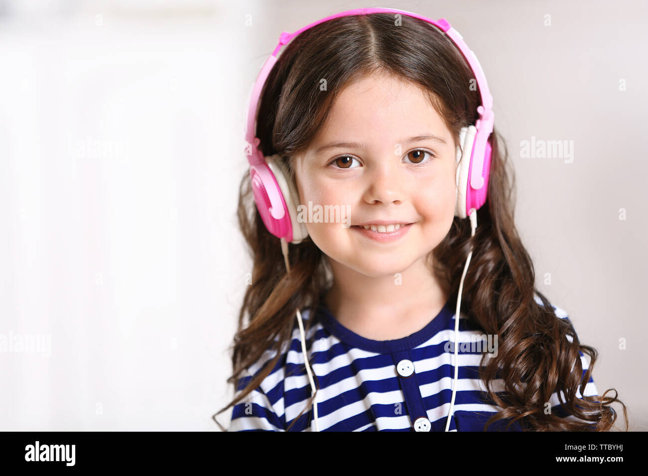 Little girl in striped dress with pink headphones in the room Stock ...