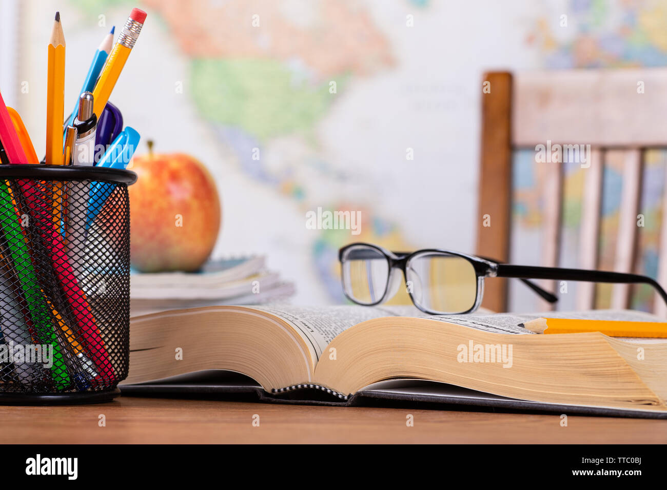 Closeup of an opened book on a school desk with world map in background ...