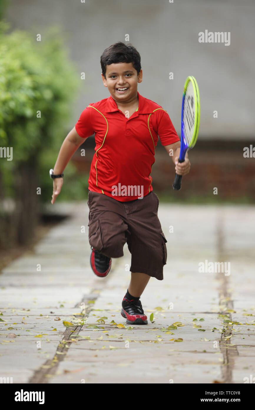 Boy running with a tennis racket Stock Photo - Alamy