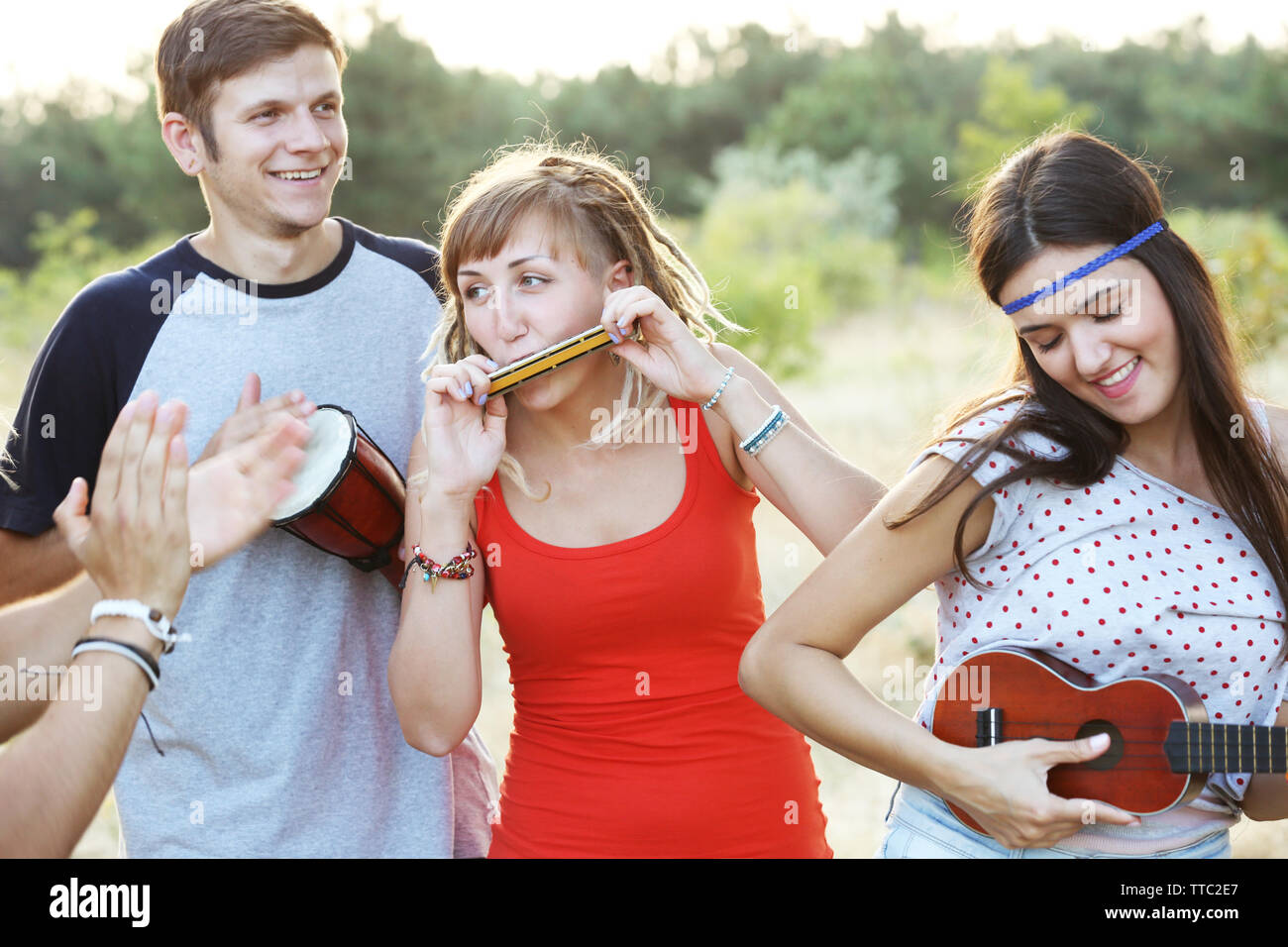 Happy smiling friends playing musical instruments in the forest ...