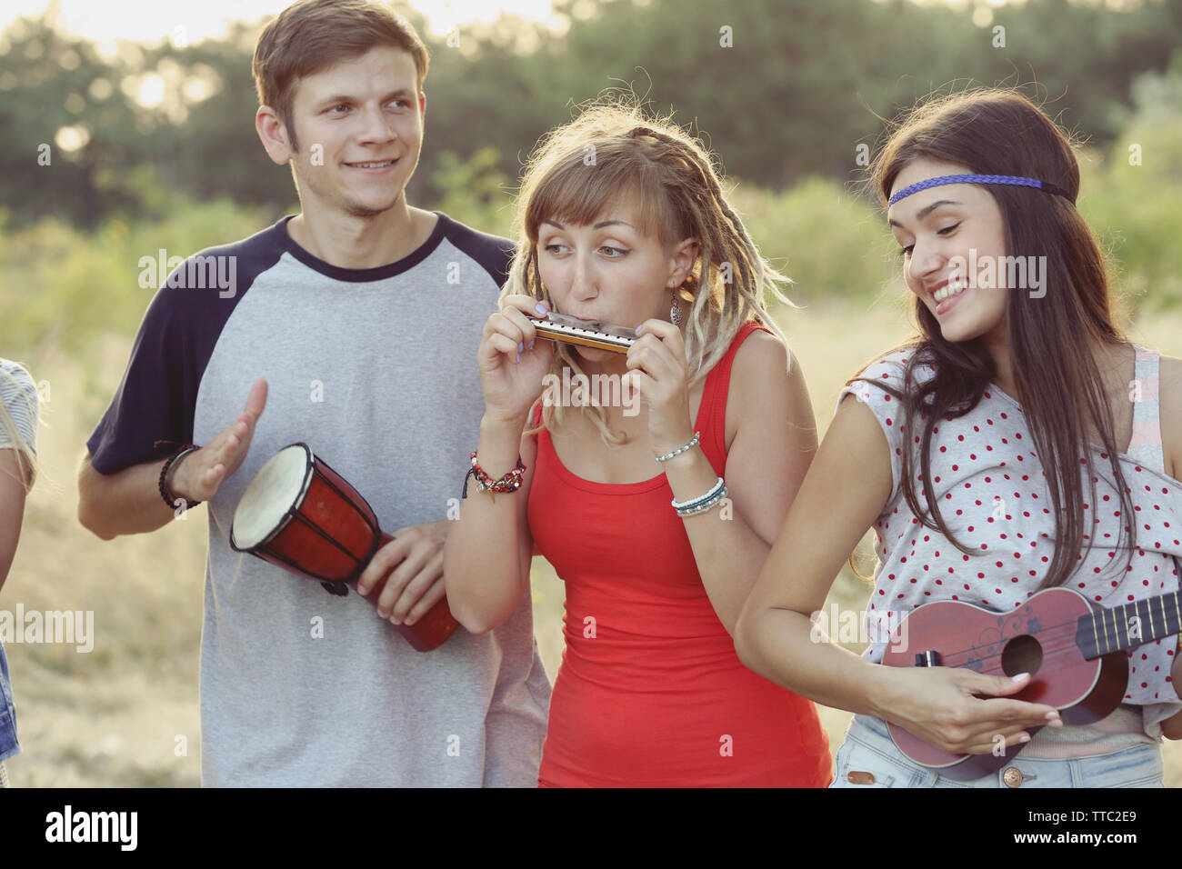 Happy smiling friends playing musical instruments in the forest ...