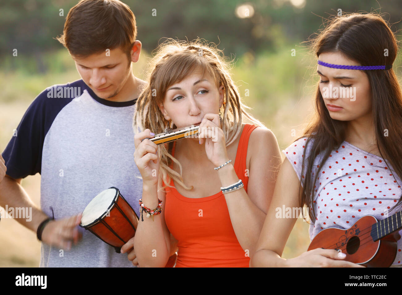 Happy smiling friends playing musical instruments in the forest ...