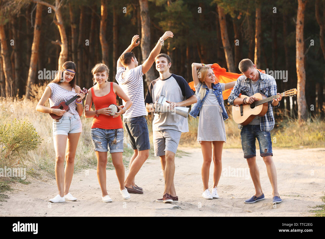 Happy smiling friends playing musical instruments in the forest ...
