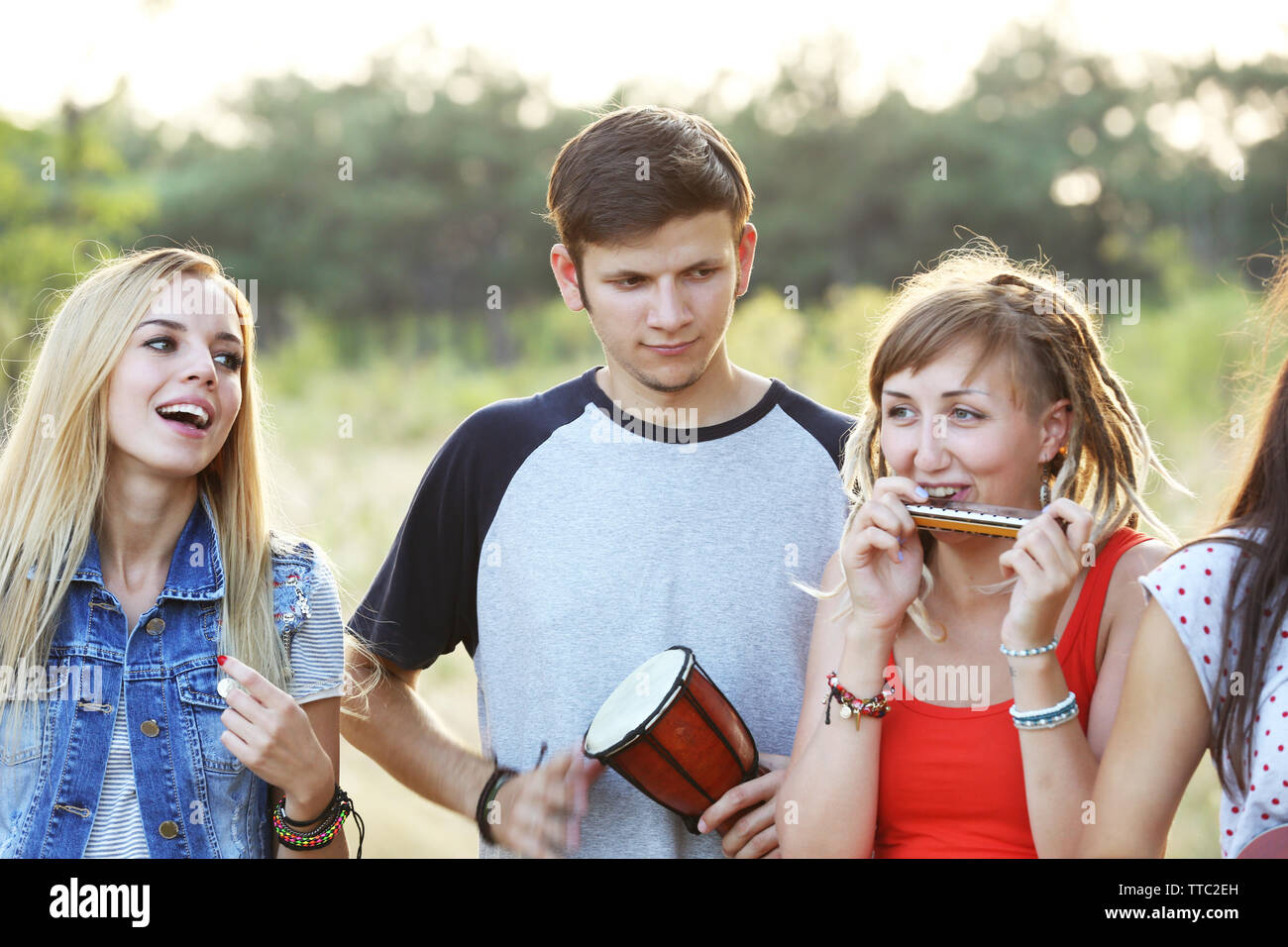 Happy smiling friends playing musical instruments in the forest ...