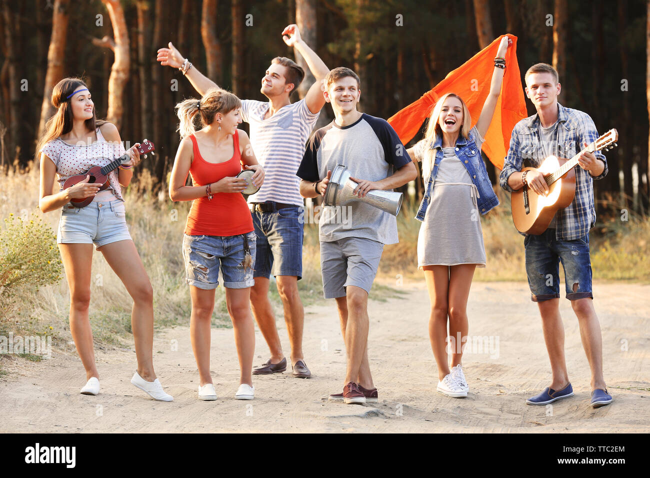 Happy smiling friends playing musical instruments in the forest ...