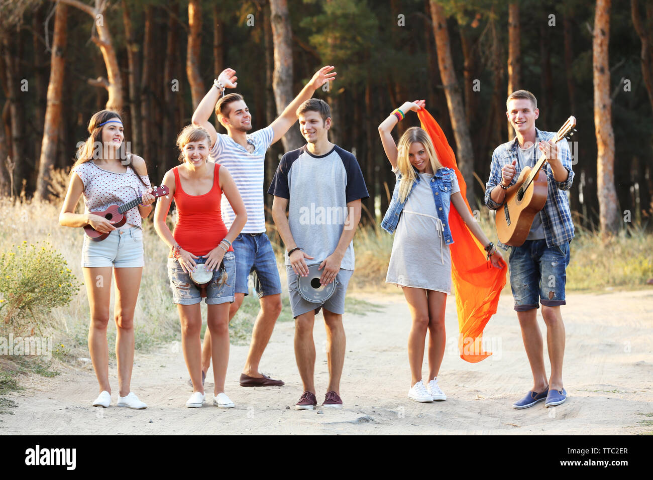 Happy smiling friends playing musical instruments in the forest ...