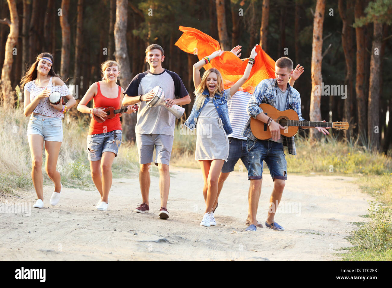 Happy smiling friends playing musical instruments in the forest ...