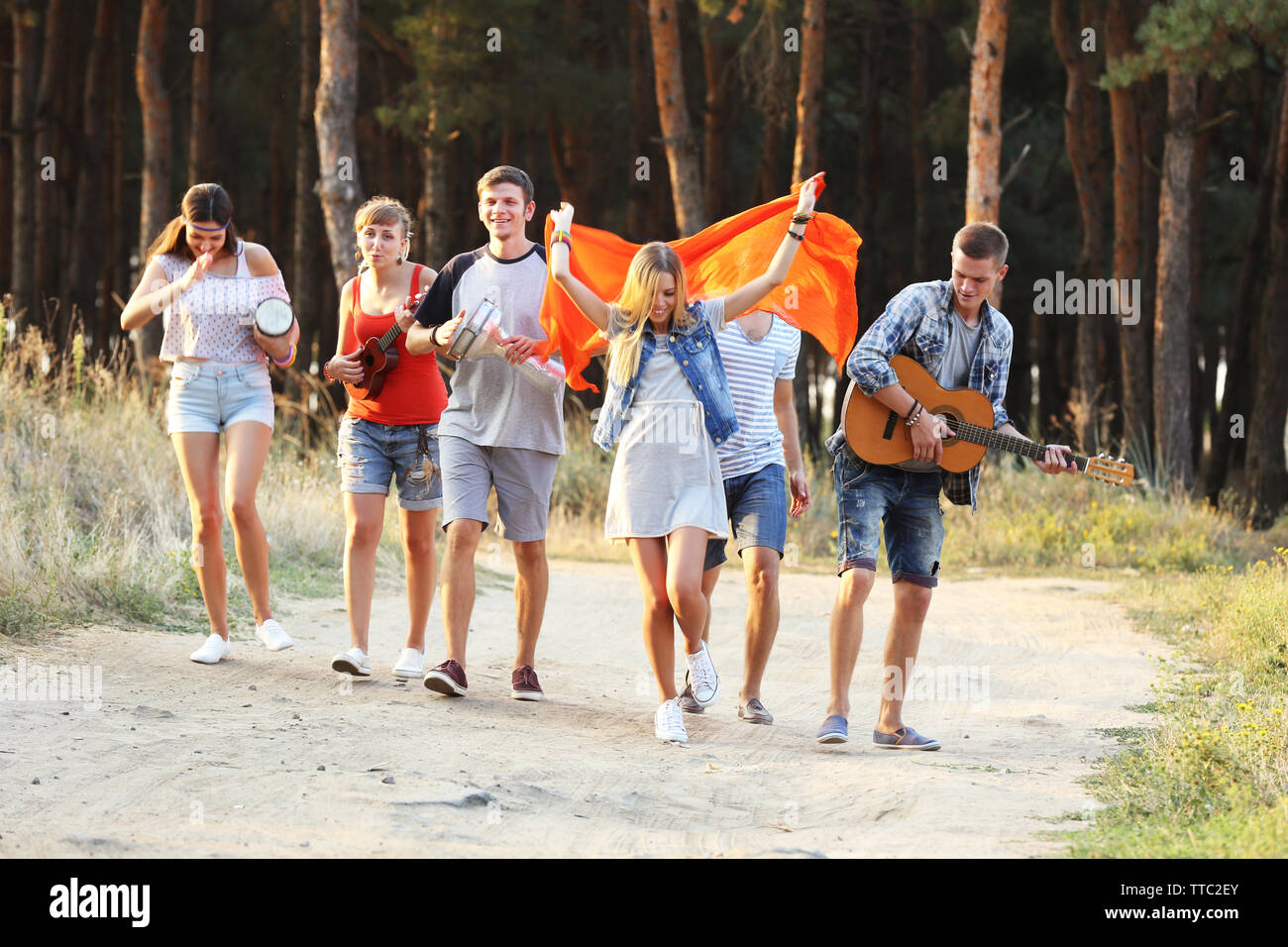 Happy smiling friends playing musical instruments in the forest ...