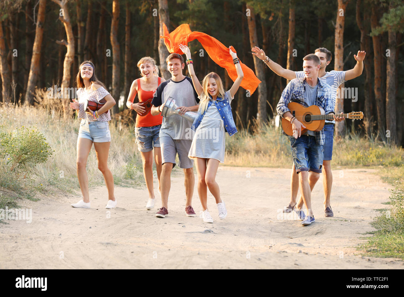 Happy smiling friends playing musical instruments in the forest ...