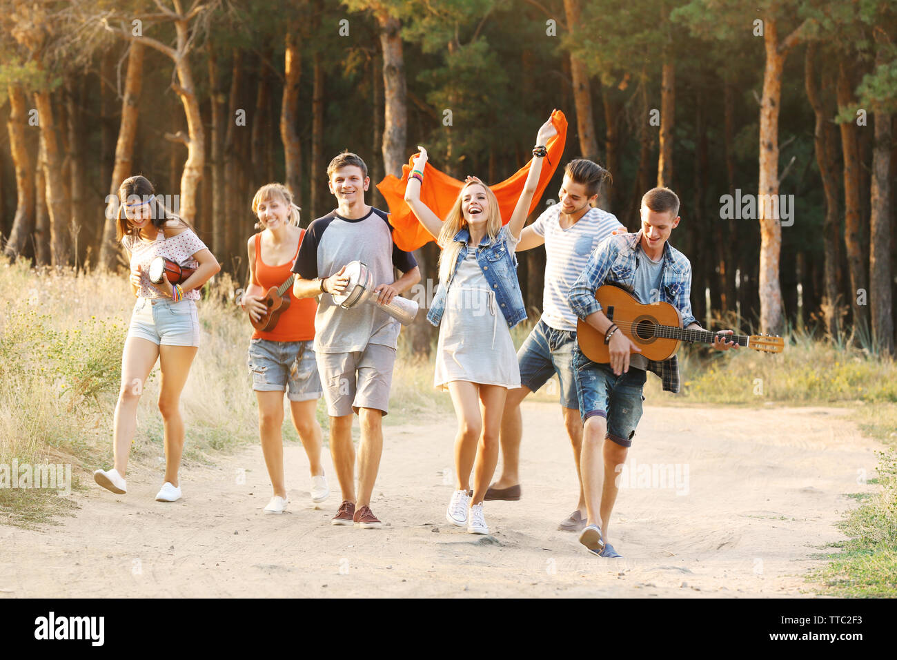 Happy smiling friends playing musical instruments in the forest ...