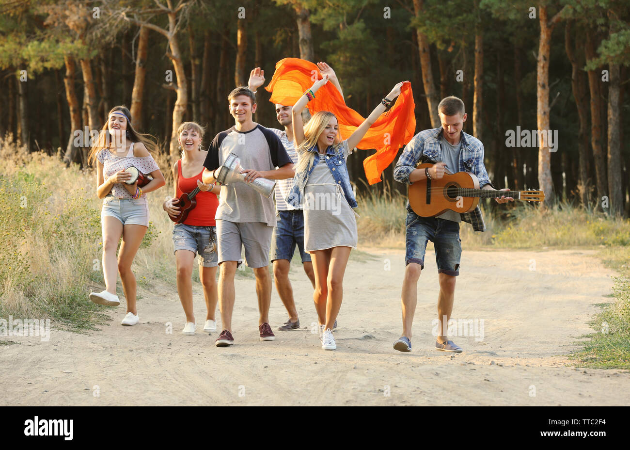 Happy smiling friends playing musical instruments in the forest ...