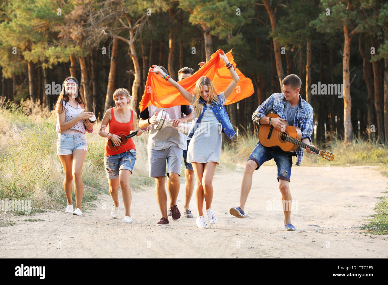 Happy smiling friends playing musical instruments in the forest ...