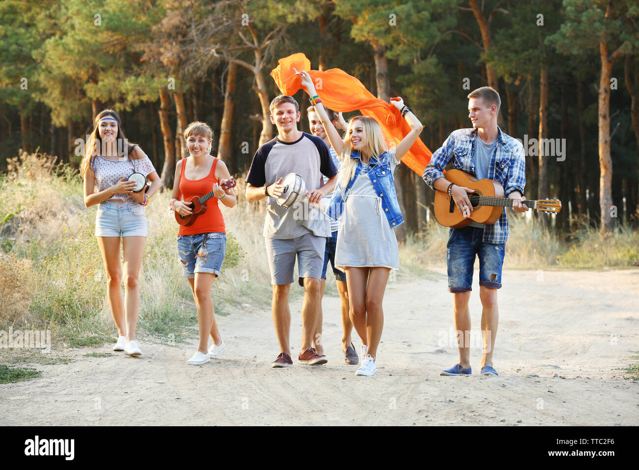 Happy smiling friends playing musical instruments in the forest ...