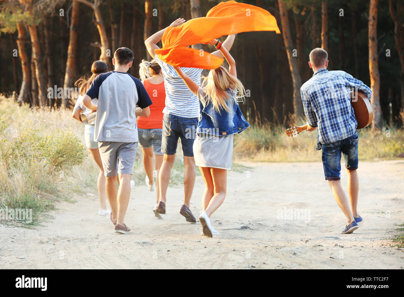 Happy smiling friends playing musical instruments in the forest ...