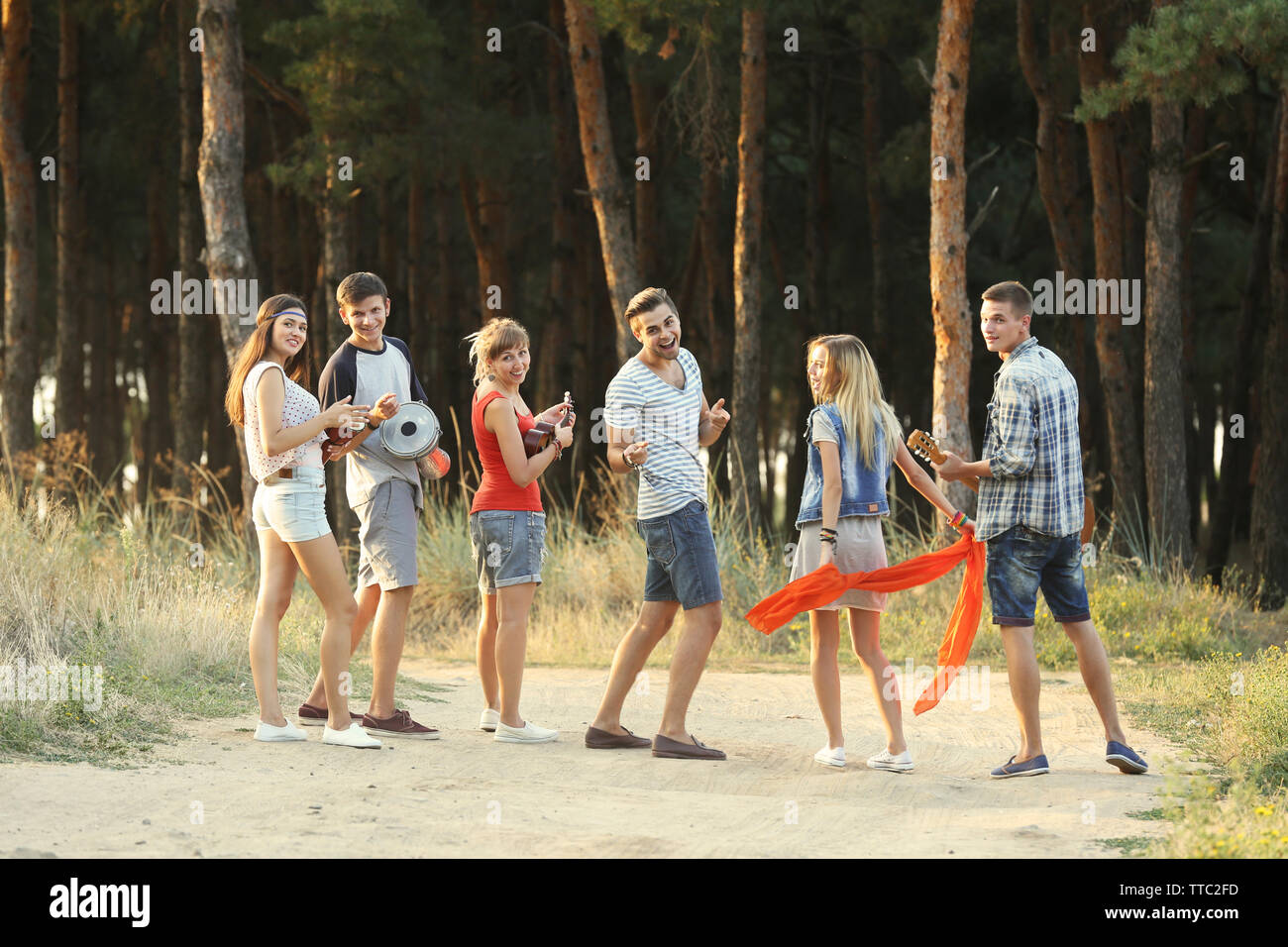 Happy smiling friends playing musical instruments in the forest ...
