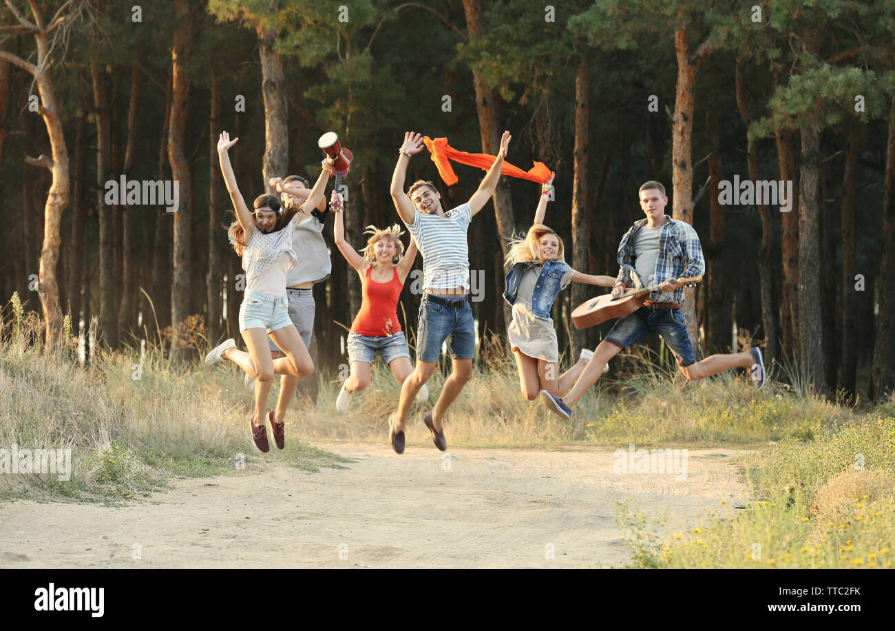 Happy smiling friends with musical instruments jumping in the forest ...
