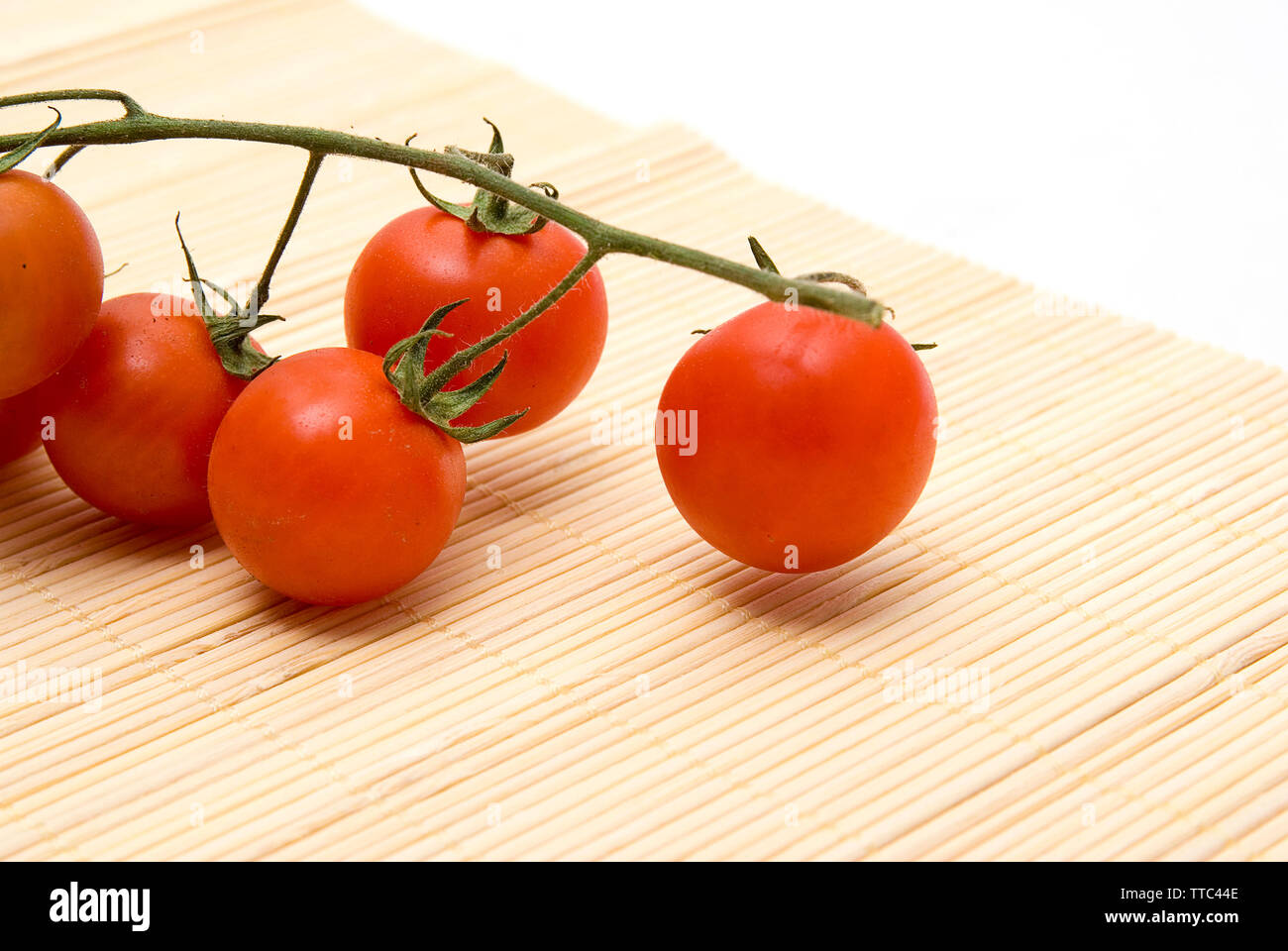 six cherry tomatoes on bamboo place mat Stock Photo - Alamy