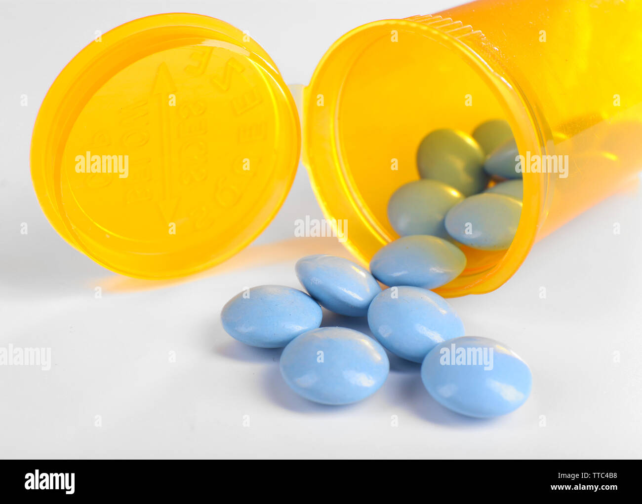Blue drugs spilled from yellow pill bottle on white background, close ...