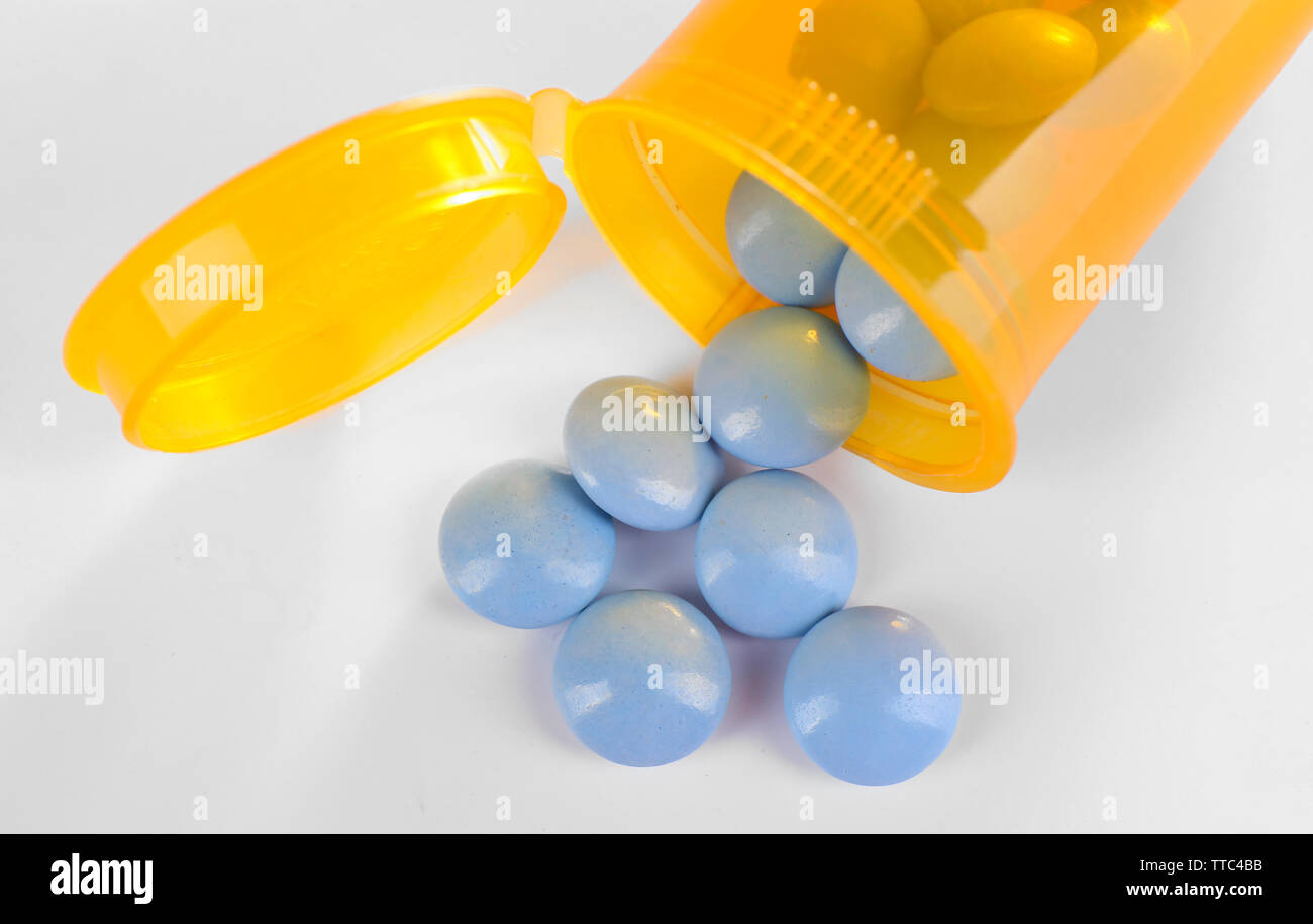 Blue drugs spilled from yellow pill bottle on white background, close ...