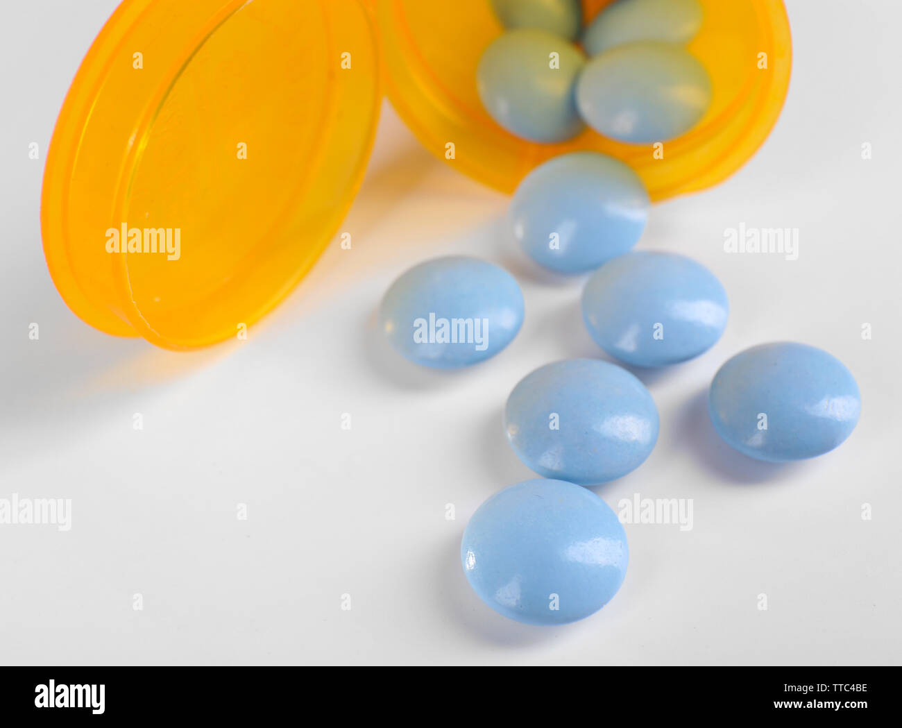 Blue drugs spilled from yellow pill bottle on white background, close ...