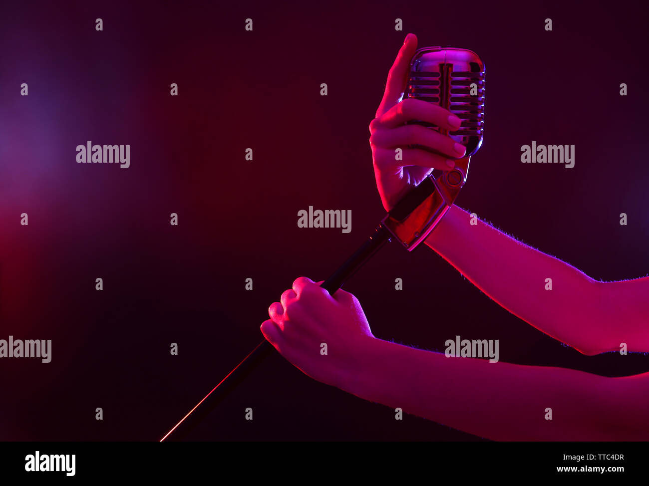 Female hand holding a retro microphone against colourful background ...