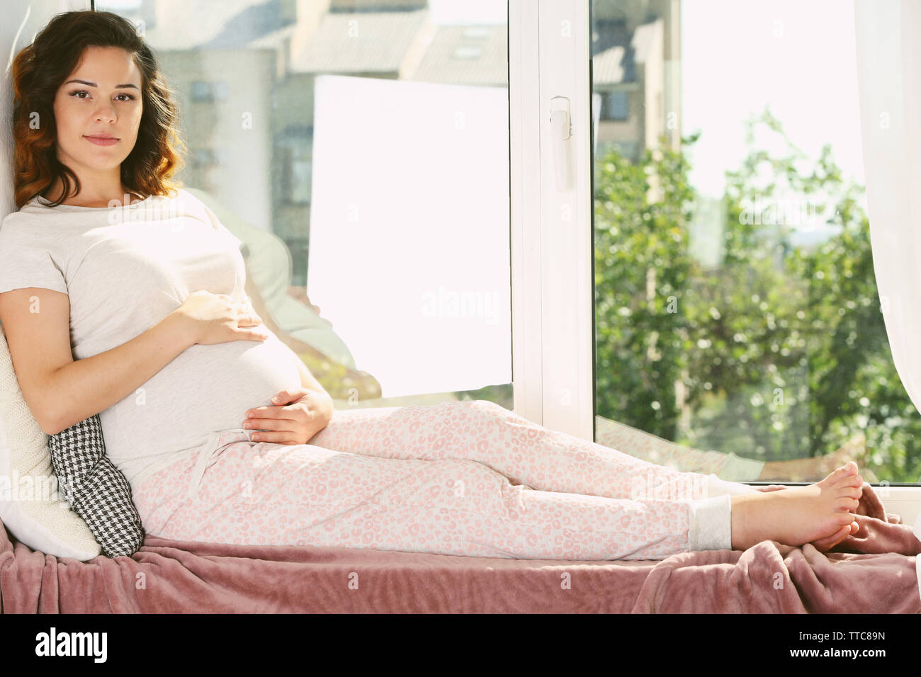 Pregnant woman on window board in the room Stock Photo - Alamy