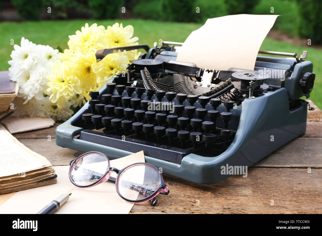 Vintage black typewriter with old books and flowers on wooden table ...