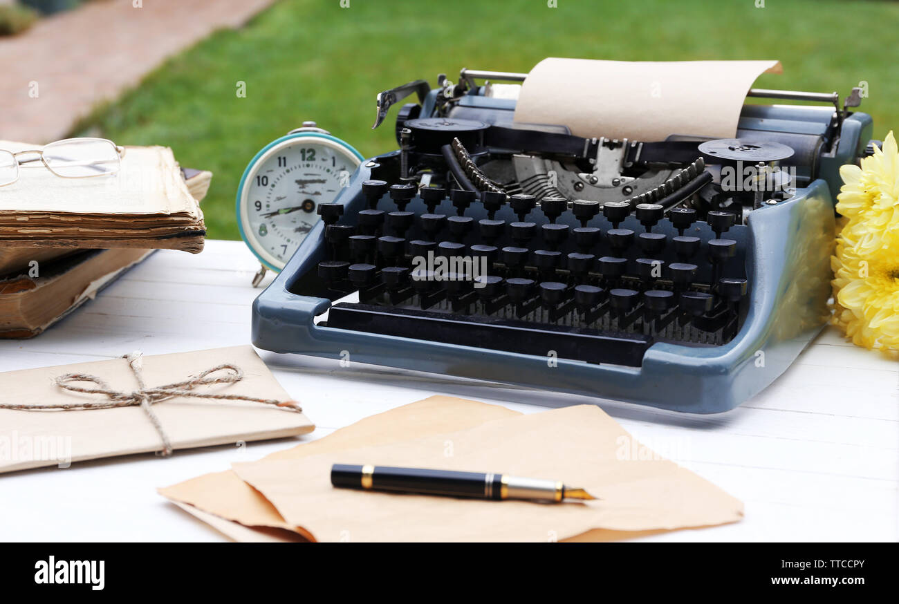 Vintage black typewriter with old books and flowers on wooden table ...