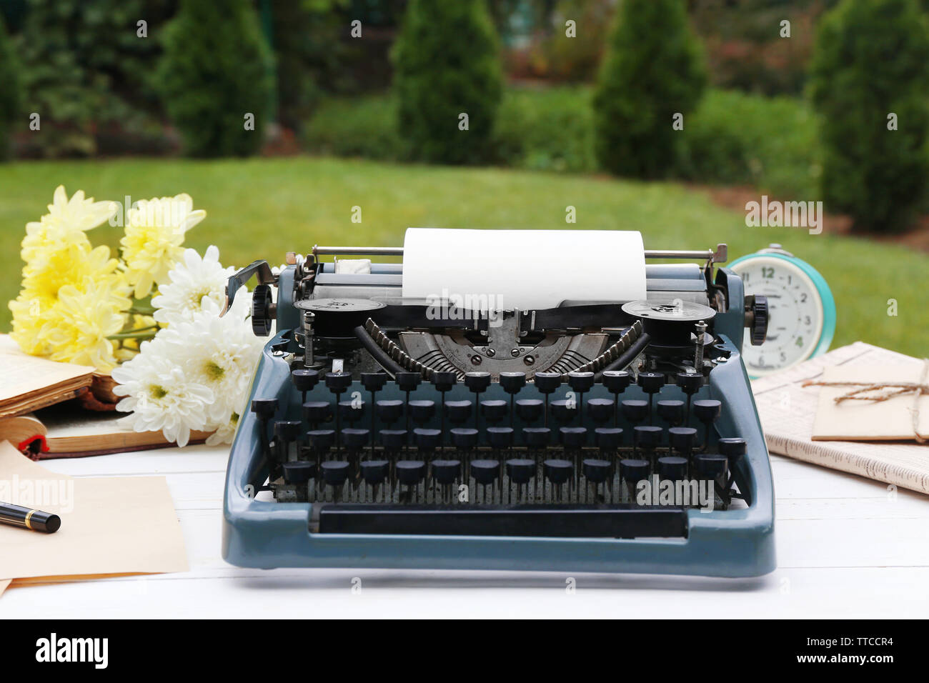 Vintage black typewriter with old books and flowers on wooden table ...