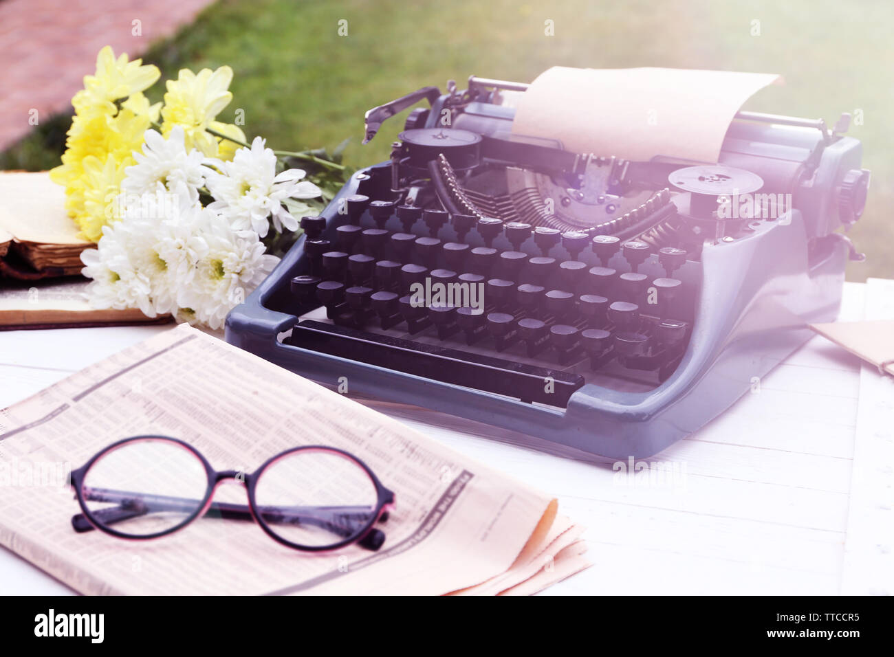 Vintage black typewriter with old books and flowers on wooden table ...