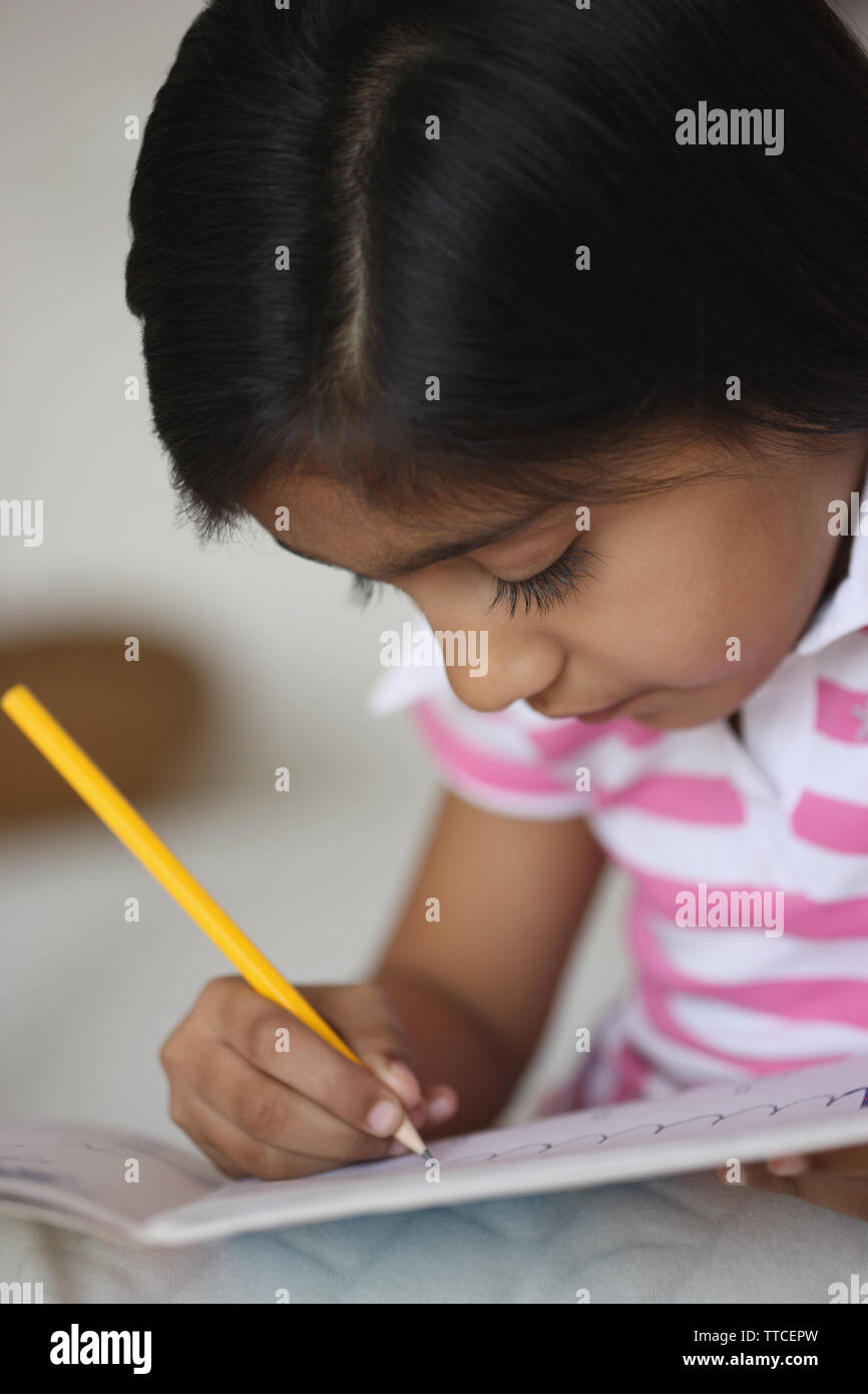 Girl writing in a workbook Stock Photo - Alamy