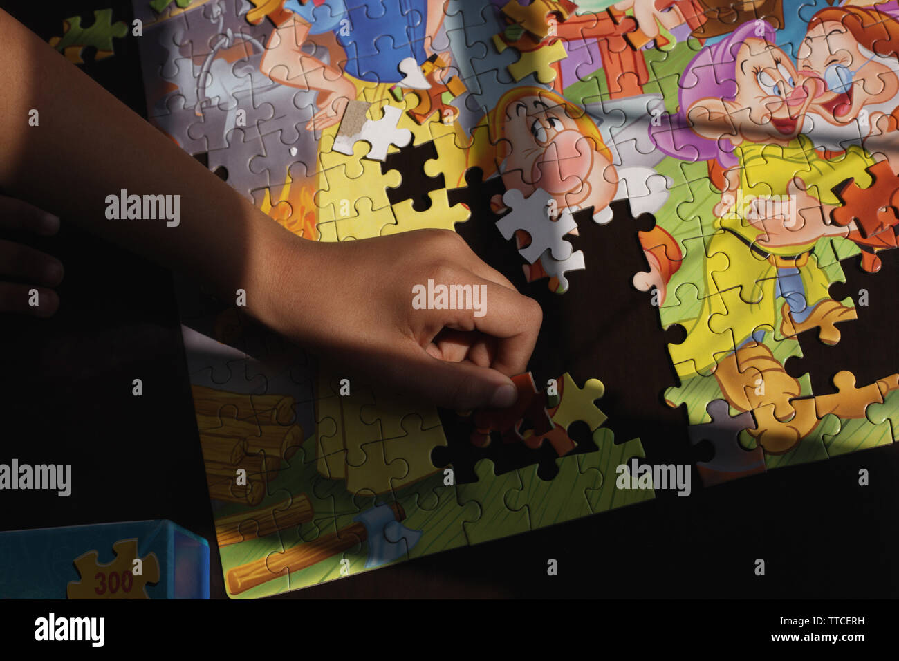 Person's hand placing puzzle pieces into jigsaw puzzle Stock Photo - Alamy