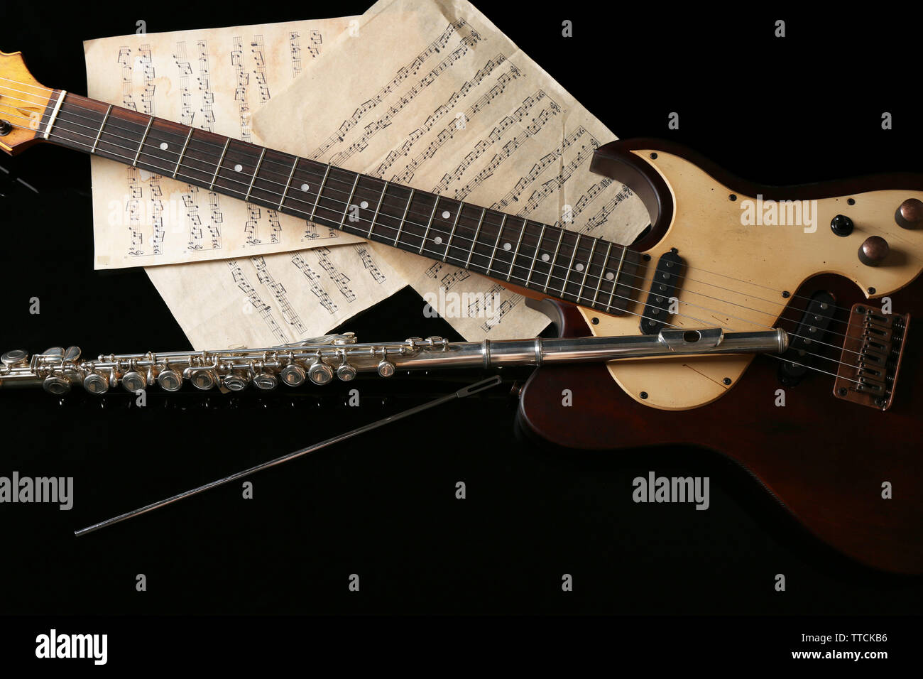 Flute, electric guitar and note sheets on black background Stock Photo ...