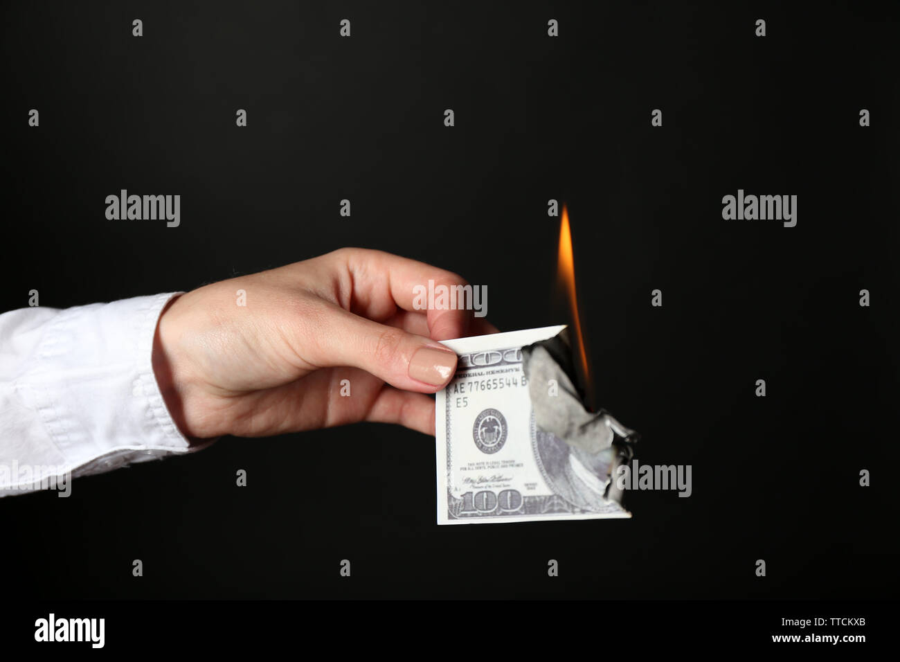 Woman burning dollars on black background Stock Photo - Alamy