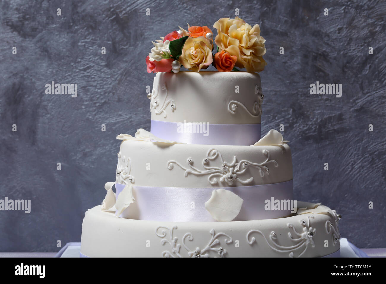 Wedding cake decorated with flowers on grey background Stock Photo - Alamy