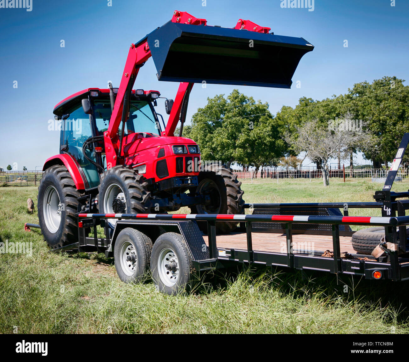 Texas farming: delivering/towing a large red tractor Stock Photo - Alamy