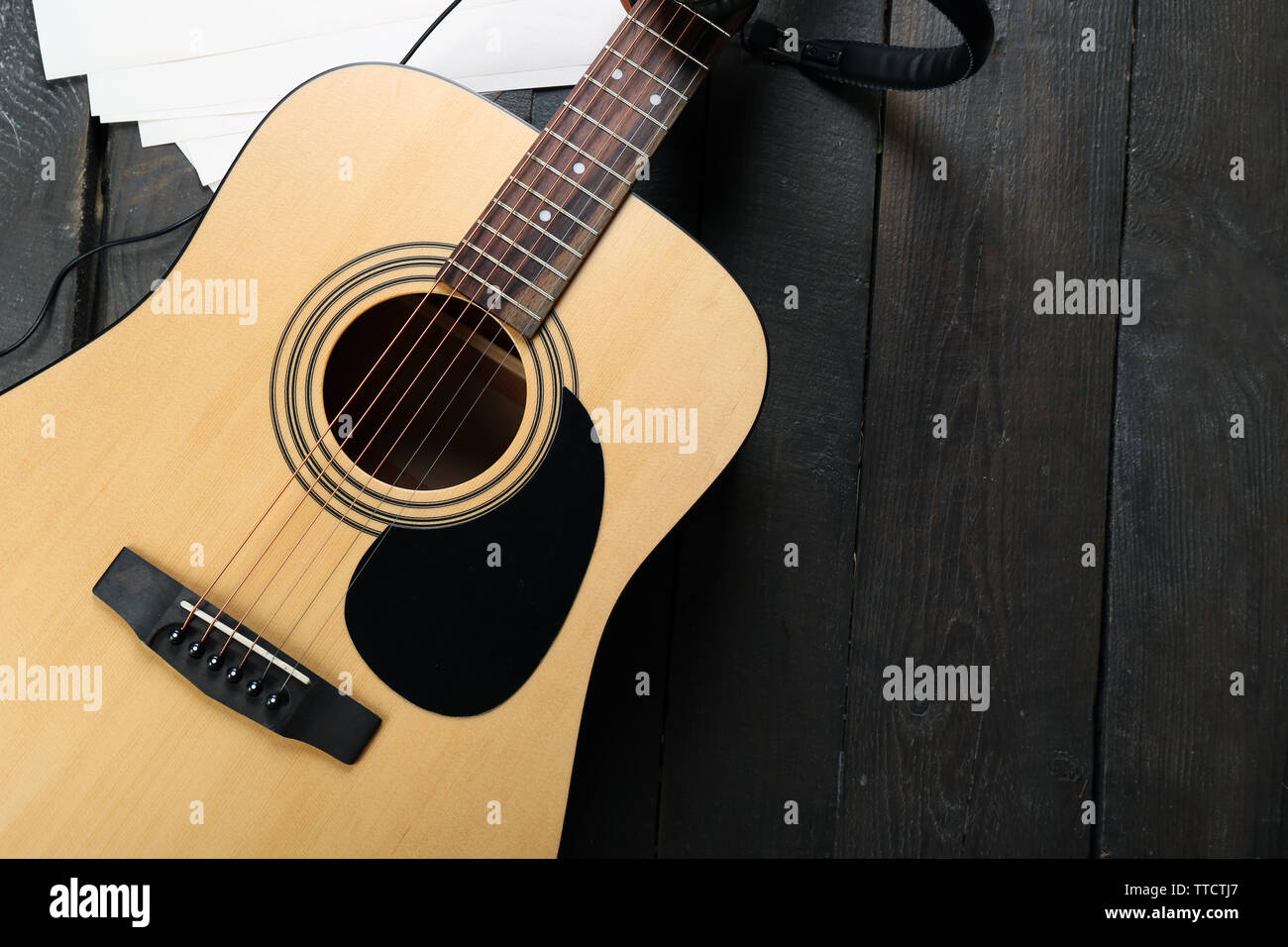 Acoustic guitar, headphones, musical notes and white papers on wooden ...