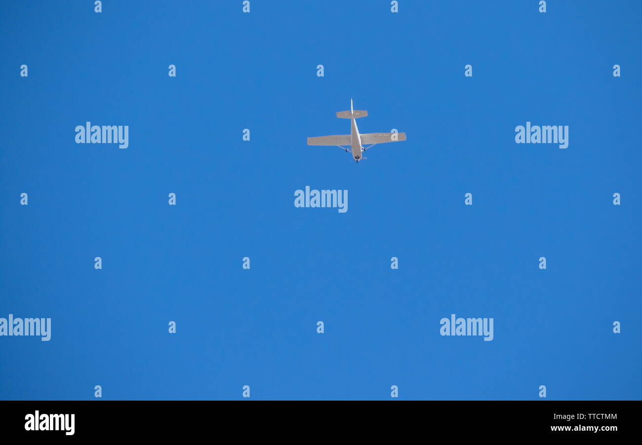 A small white fixed wing aircraft isolated against a blue sky image ...