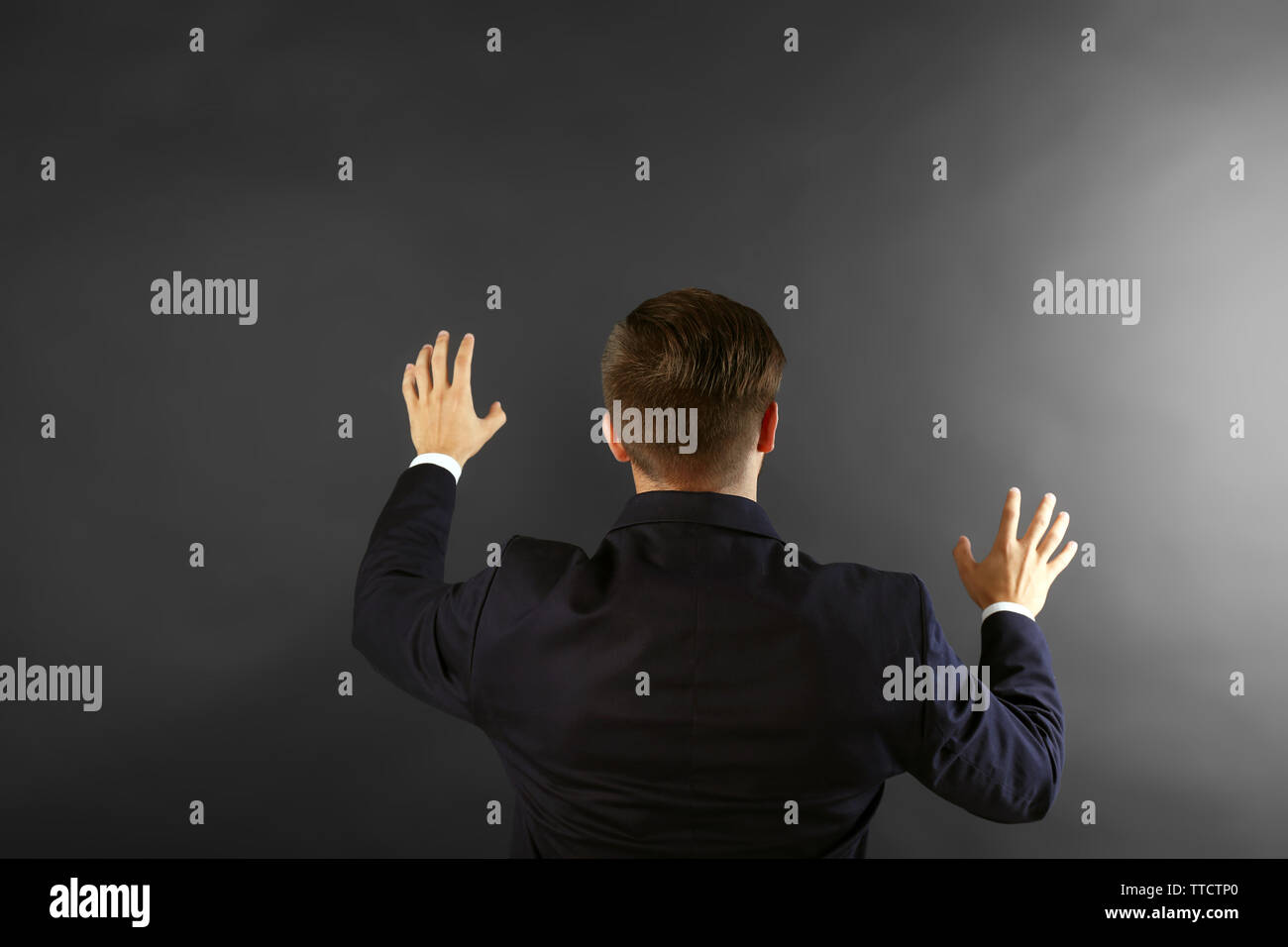 Back view of Caucasian young man in navy blue suit pointing on dark ...