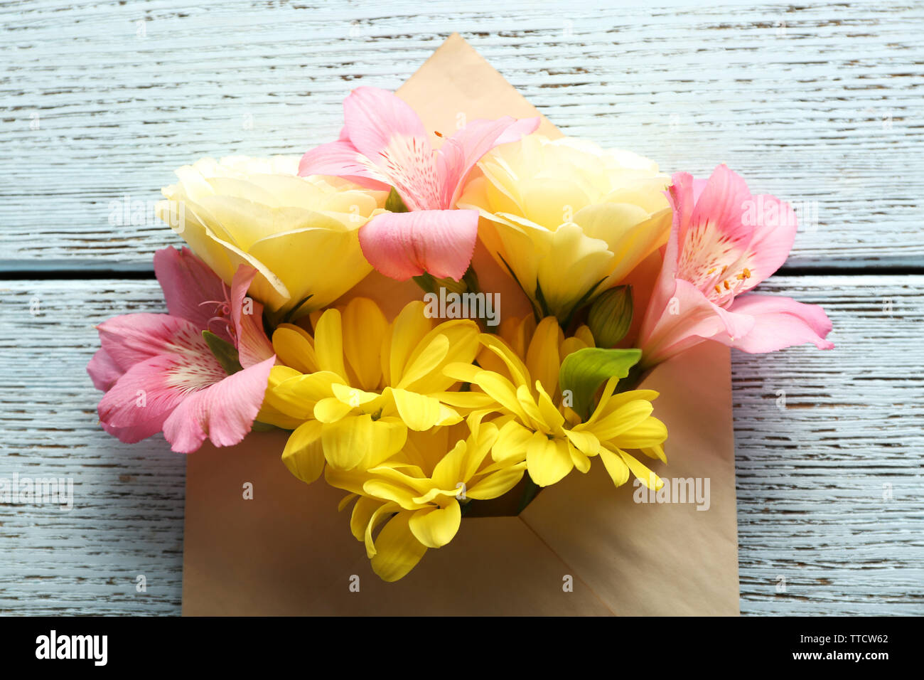 Fresh bouquet of flowers in envelope on wooden background Stock Photo ...