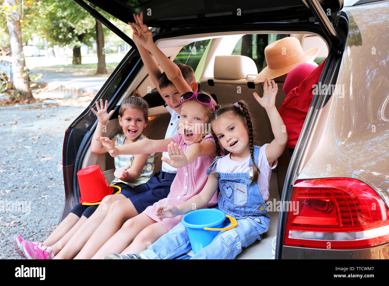 Happy children sitting on a car trunk Stock Photo - Alamy