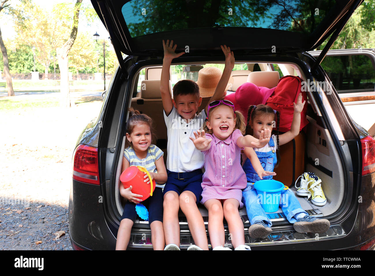 Happy children sit on a car trunk and laughing Stock Photo - Alamy