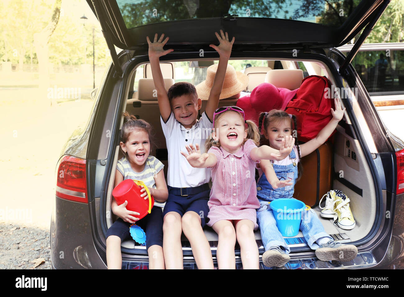 Happy children sit on a car trunk and laughing Stock Photo - Alamy