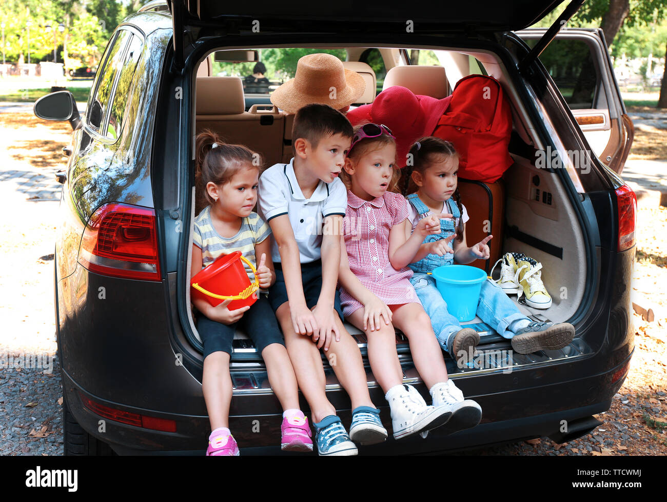 Happy children sit on a car trunk and laughing Stock Photo - Alamy