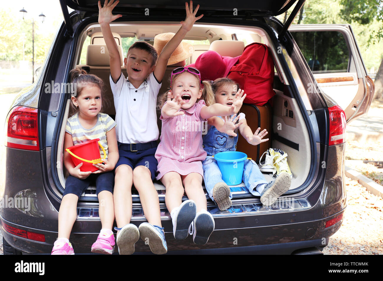 Happy children sit on a car trunk and laughing Stock Photo - Alamy