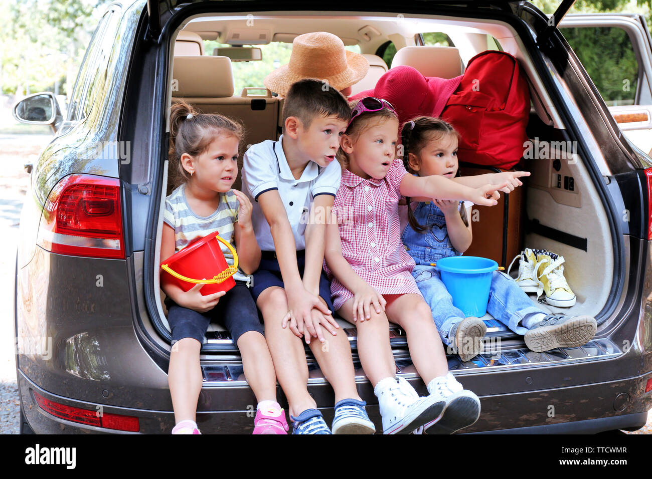 Happy children sit on a car trunk and laughing Stock Photo - Alamy