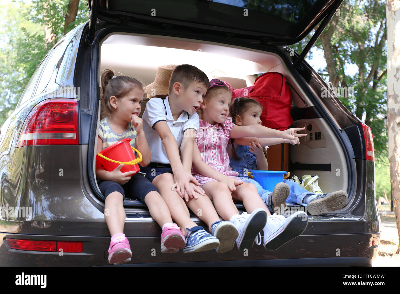 Happy children sit on a car trunk and laughing Stock Photo - Alamy