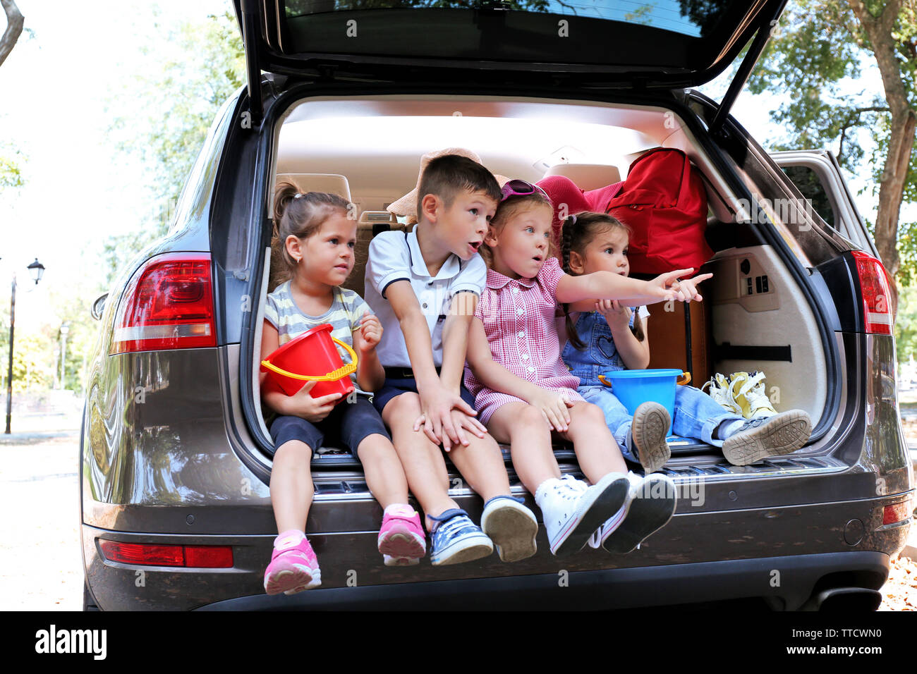 Happy children sit on a car trunk and laughing Stock Photo - Alamy