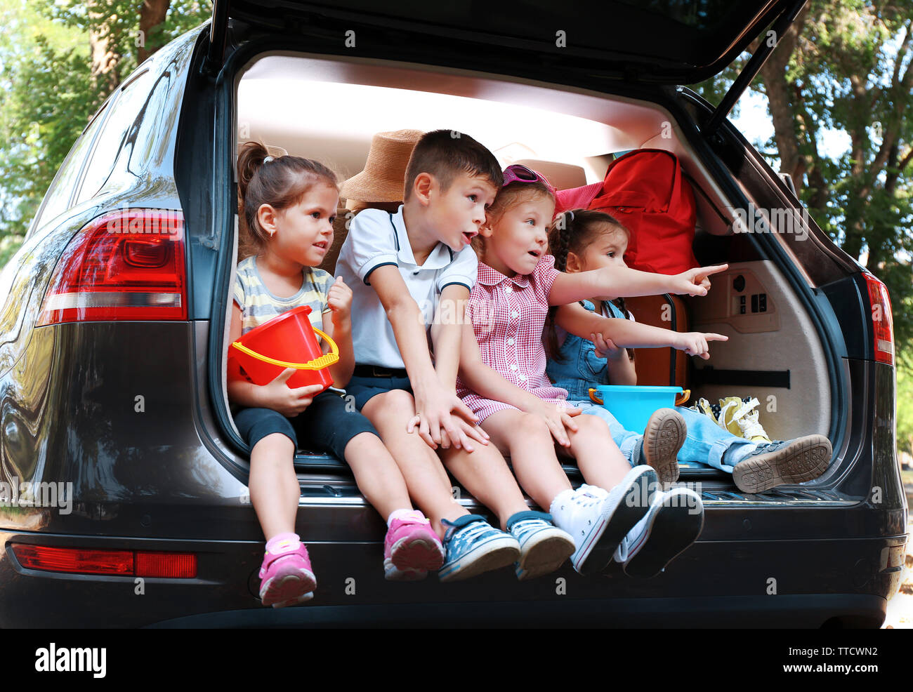 Happy children sit on a car trunk and laughing Stock Photo - Alamy