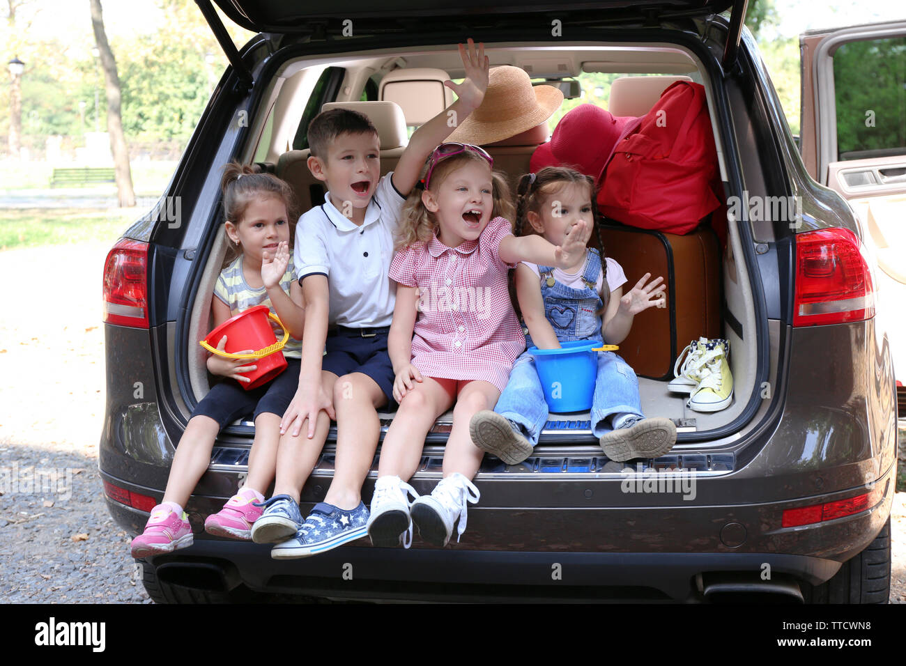 Three beautiful girls and boy sit on a car trunk and laughing Stock ...